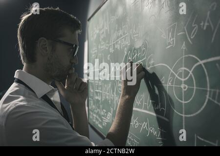 Young mathematician solving problems and writing formulas on the ...