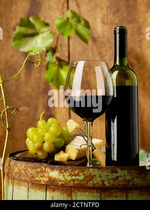 Red wine, cheese, bread and grapes on wooden table on background with ...