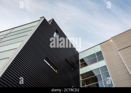 generic office building with glass facade reflecting sky and clouds ...