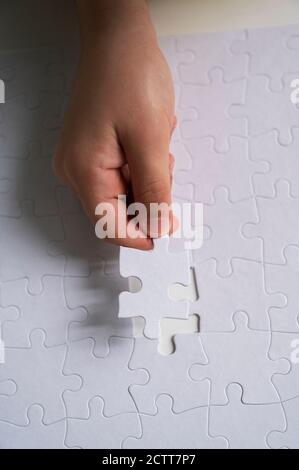 Hand arranging the puzzle pieces on a white surface Stock Photo - Alamy