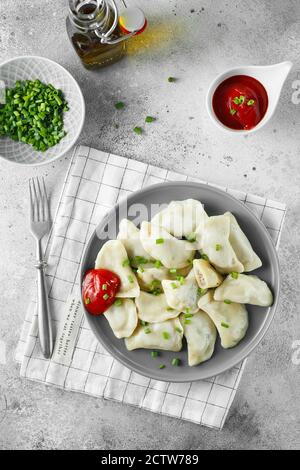 Flat lay composition of bowl of dumplings, jar of sour cream on wooden ...