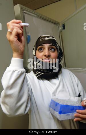 A hospital lab technician holds up a frozen test tube with a sample of ...
