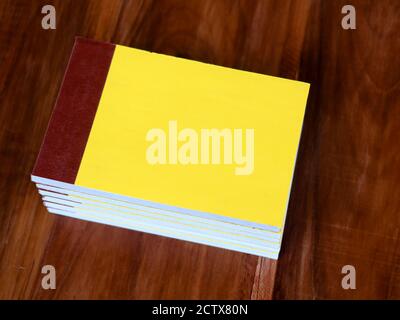 Yellow color bill books or receipt books on a wooden surface, close up ...
