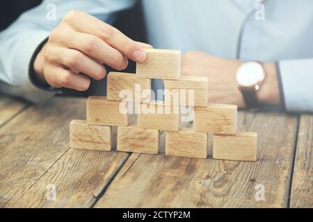 Businessman gambling placing wooden block on a tower Stock Photo - Alamy