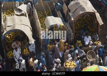 Pakistani farmers busy in their trucks loaded with watermelon at a ...
