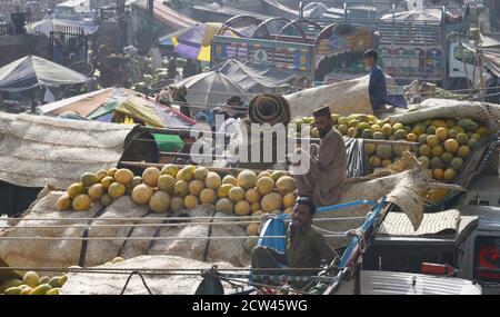 Pakistani farmers busy in their trucks loaded with watermelon at a ...