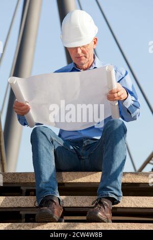 Construction worker reading plan at construction site Stock Photo - Alamy