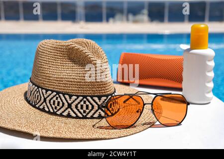 orange coloured beach accessories near swimming pool. Sun cream ...