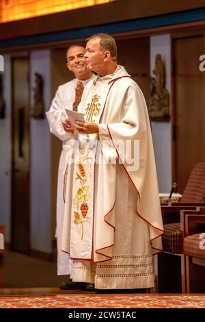 Wearing ceremonial robes, a priest and his deacon confer while ...