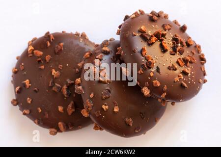 Three mini biscuits with cocoa on a clay plate, macro, isolated on a ...