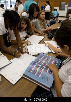 Hispanic middle school girls wearing blue graduation gowns await ...