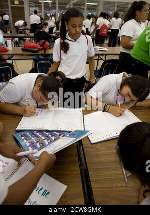 Hispanic middle school girls wearing blue graduation gowns await ...