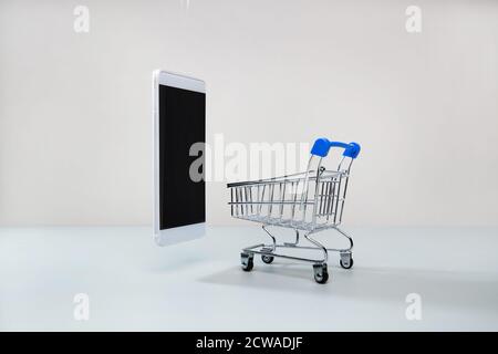 Mobile phones and mini shopping cart Stock Photo - Alamy