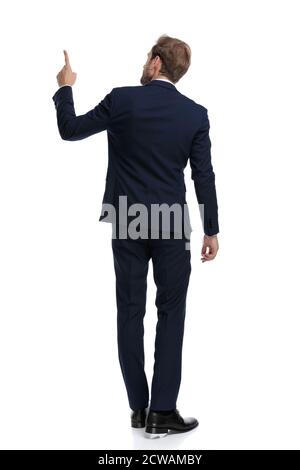 Handsome businessman in suit pointing, looking left at logo with ...