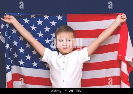 Happy caucasian 9s Boy holding big American flag, on blue background ...
