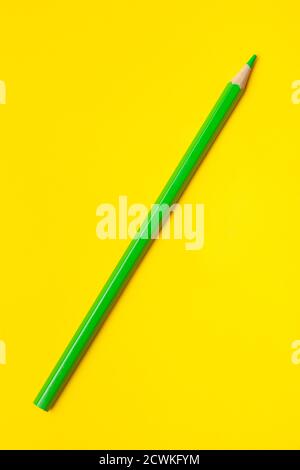 diagonal green sharp wooden pencil on a bright yellow background ...
