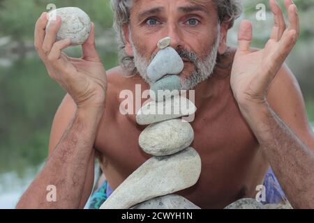 Mature man doing stone piles along the river Stock Photo - Alamy