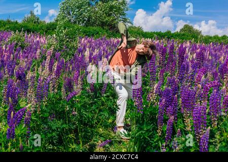 Tall handsome man dancing on lupine flowers field Stock Photo - Alamy