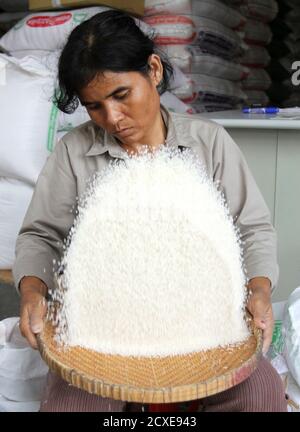 A woman separates rice grains from grains and the glumes, or husks ...