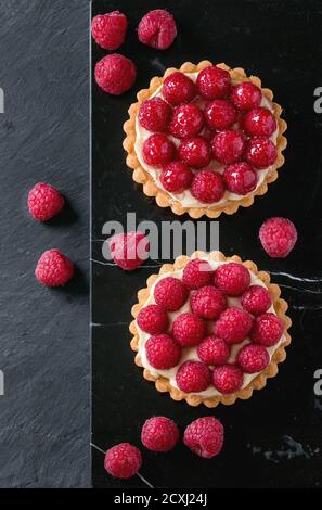 Ripe raspberries on a black stone concrete background. Small buckets ...