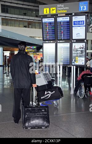 Passengers looking at flight information display board showing ...