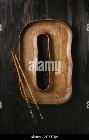 Empty plate (dark) and Chinese chopsticks on a dark background. Asian ...