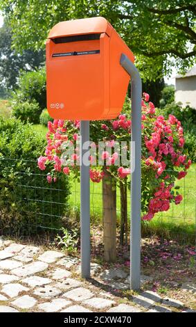 Typical Dutch orange letterbox with PostNL logo, which is outside in a ...