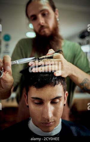 Close-up of the hand of a skilled barber using scissors, while trimming ...