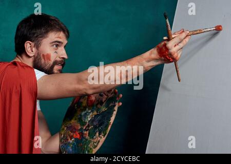 Male artist red cloak drawing easel art green background image Stock ...