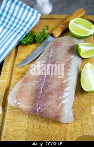 raw fish fillet (saithe) on a cutting board Stock Photo - Alamy