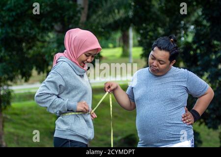 Two people, muslim woman and fat man, proportional and over weight ...