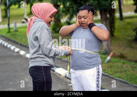 Two people, muslim woman and fat man, proportional and over weight ...