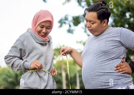 Two people, muslim woman and fat man, proportional and over weight ...