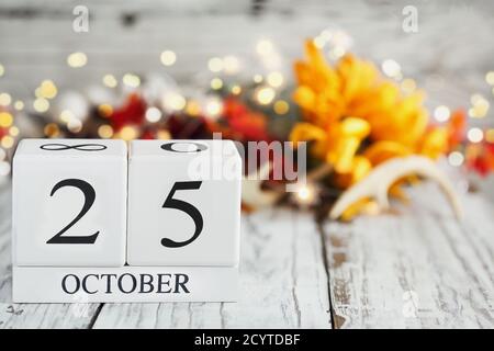 October 25 wooden calendar, white on a black background, pink roses lie ...