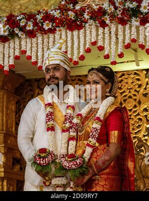 At a Hindu wedding, the bride & groom are seated with their hands ...