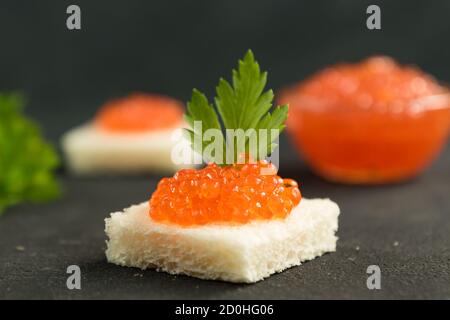 Square shaped sandwich with red caviar on black background Stock Photo ...