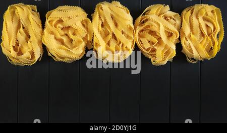 Italian pasta. Curly pappardelle pasta on dark background. View from ...