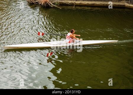 A man sculling in a single scull rowing boat, on the water. Overhead ...