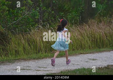 Five-year-old girl running with her father on a country road. Dressed ...