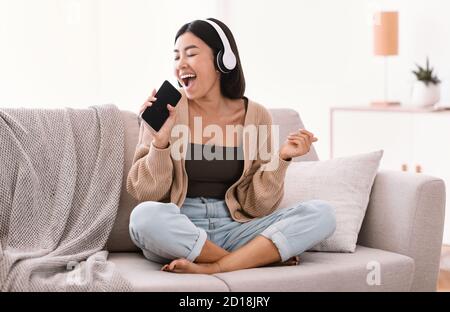 Asian lady singing favorite song and using cell phone as a mic Stock ...