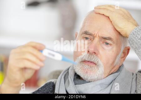 Mature sick man checking body temperature with thermometer Stock Photo ...