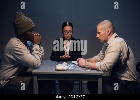 A black drug addict is interrogated at a police station by an ...