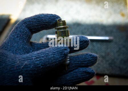 Hand with glove holding spark plug with blurred background Stock Photo ...