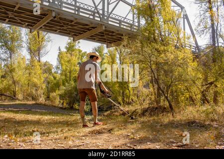 Prospector man uses a metal detector for lost gold treasure from the ...