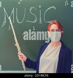 Woman musician with flute in medical face mask on studio black ...