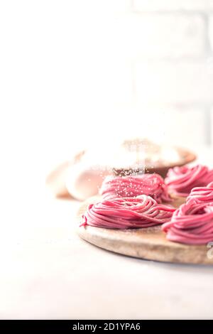 Fresh Hand made beetroot pasta on wooden cutting board. Raw purple ...