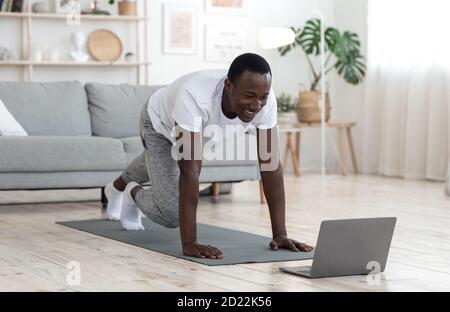 Joyful millennial black man with laptop celebrating online win or work ...