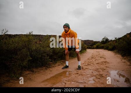 Tired wet athletic man in sports blue t-shirt wiping sweat his hand on ...