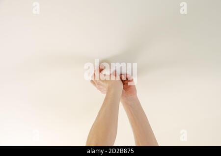 Men's hands cut a hole for a recessed spotlight in a suspended ceiling ...