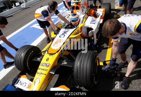 F1 mechanics at work on a Renault F1 race car in the pit lane workshop ...